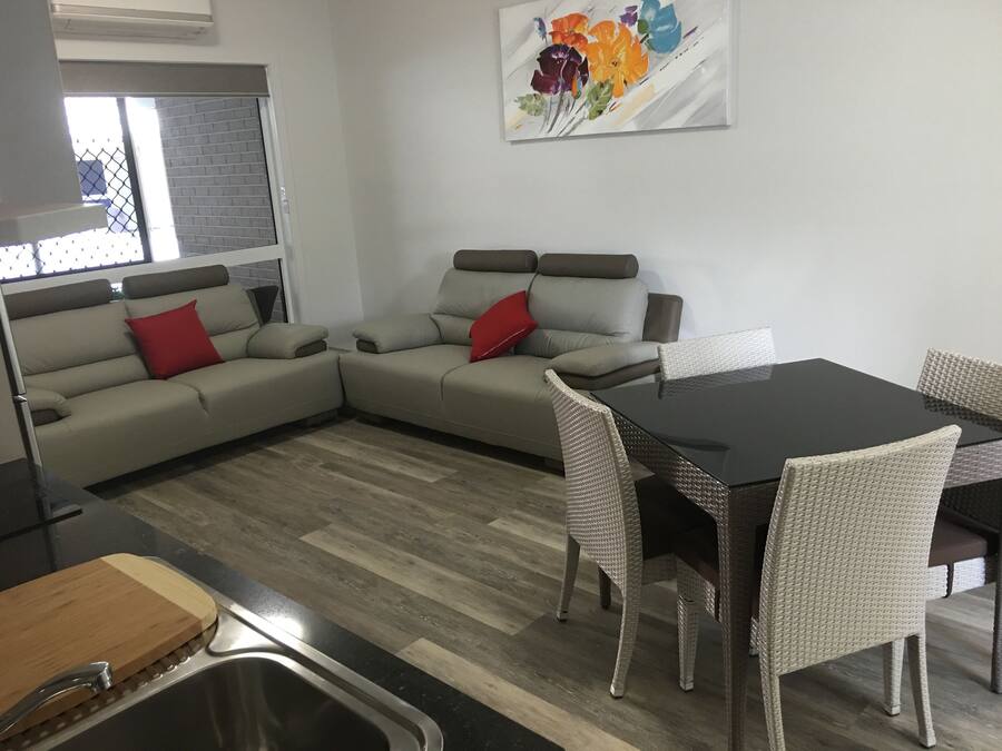 Uma cozinha moderna com área de refeições, com um conjunto de sofás, uma mesa de jantar e uma pia.