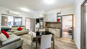 Um apartamento moderno com sala de estar, área de refeições, cozinha e um quarto.