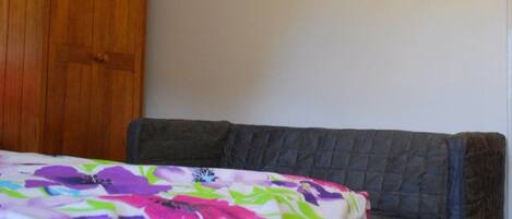 Quarto com cama, guarda-roupa de madeira e pintura de um veleiro na parede.