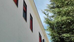 Um edifício branco com persianas vermelhas e grades de metal.