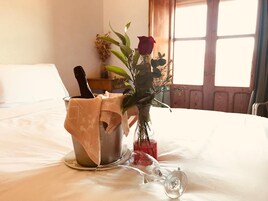 Uma cama com um balde de metal contendo uma rosa e uma garrafa de vidro.