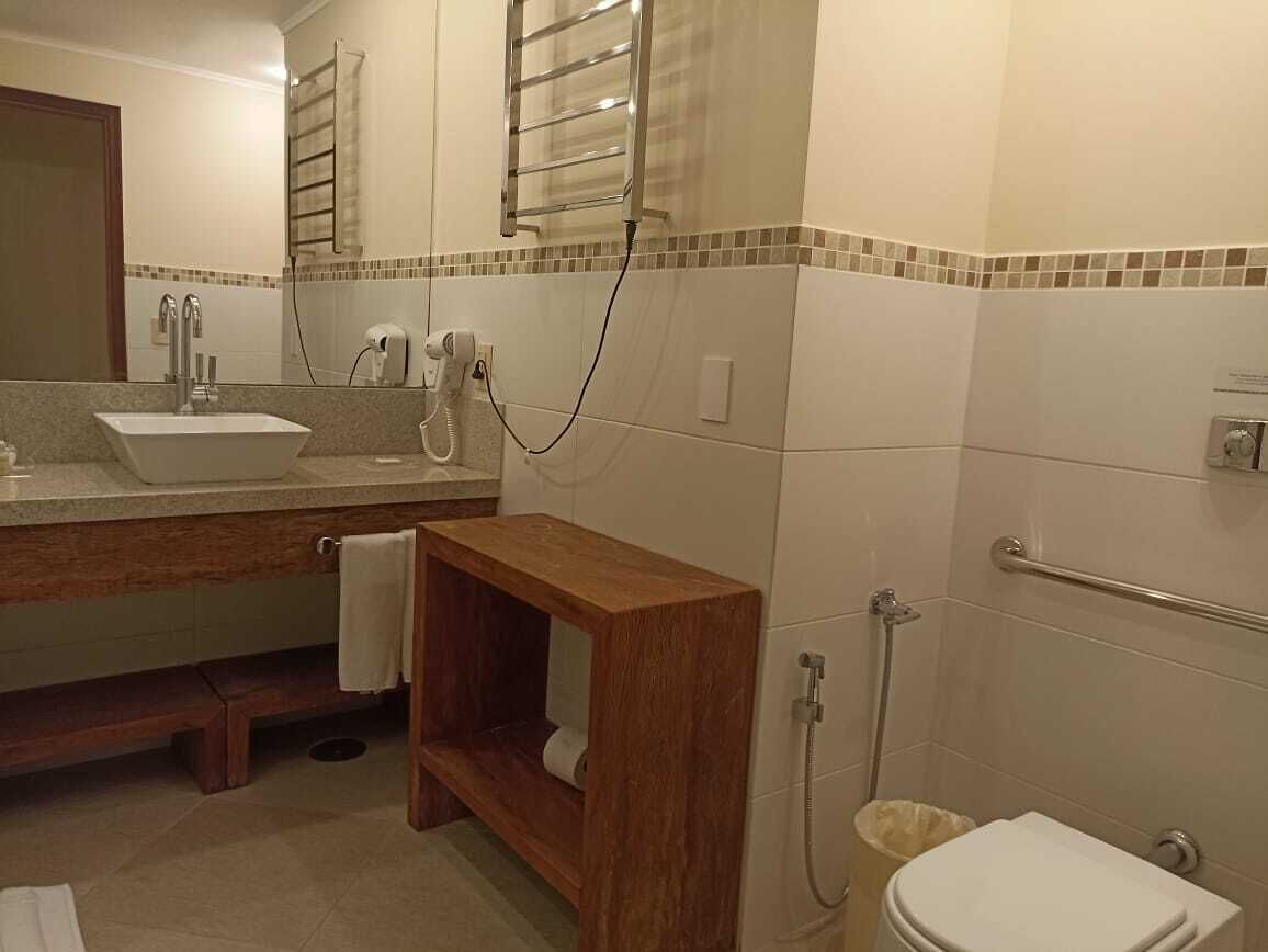Casa de banho com lavatório, espelho, porta-toalhas e sanita.