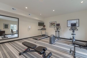 Sala de ginástica equipada com esteira, elíptica, bicicleta ergométrica e banco de musculação.