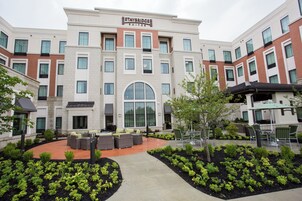 Hotel Staybridge Suites com um pátio central, mobiliário de exterior e jardins bem cuidados.