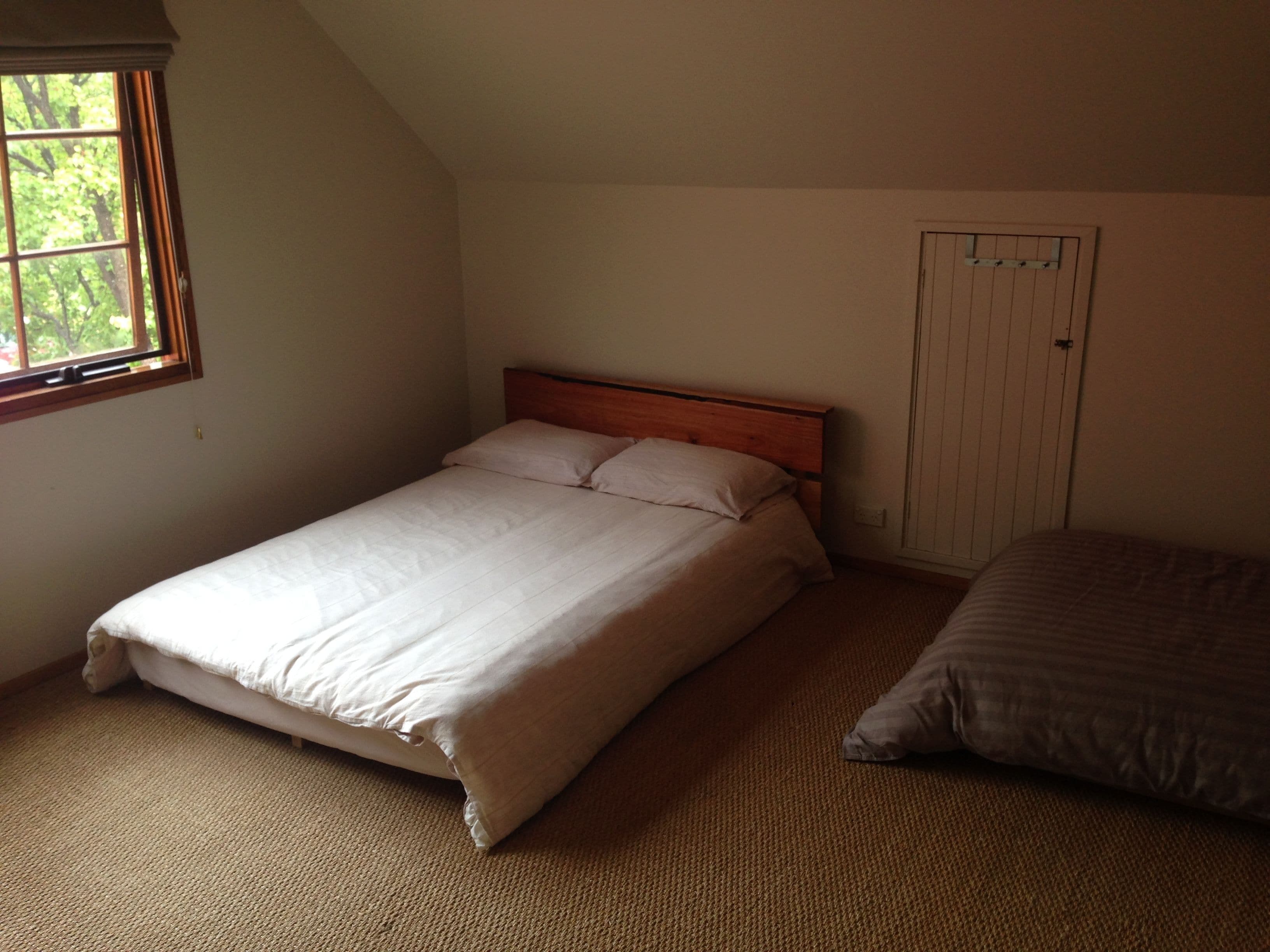 Quarto com uma cama de solteiro, janela e porta.