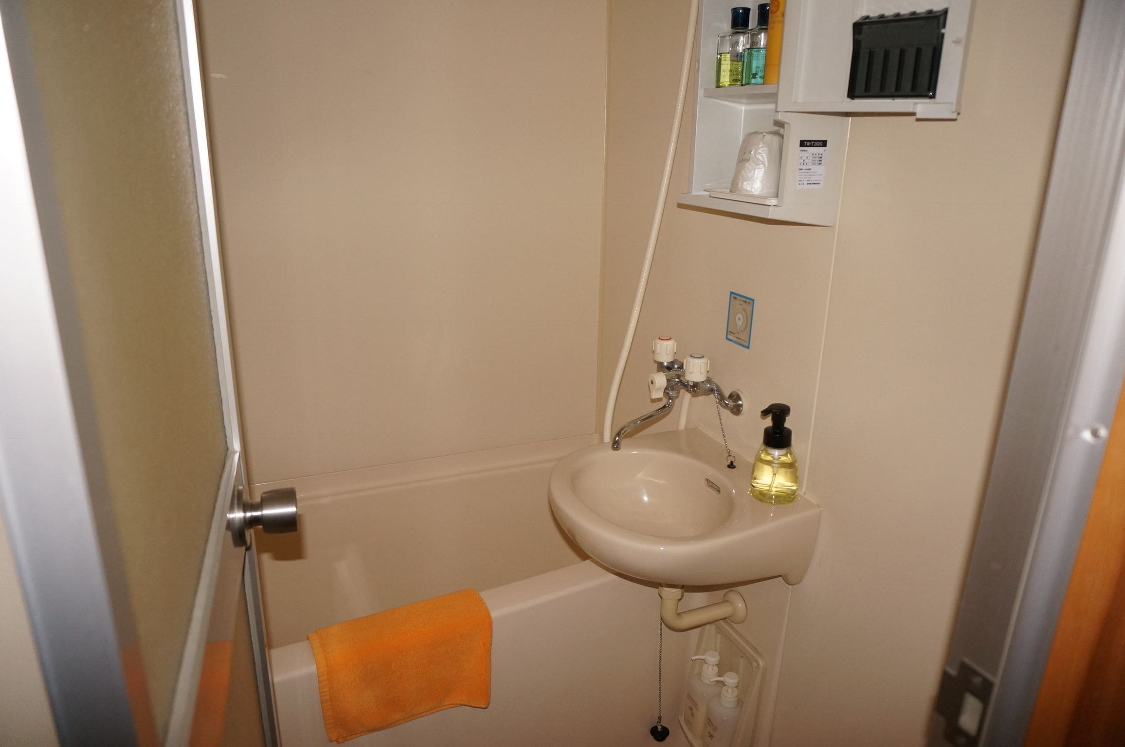 Casa de banho com banheira, lavatório e prateleira com produtos de higiene pessoal.