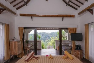 Quarto de hotel com cama, televisão, escrivaninha e vista para as montanhas.