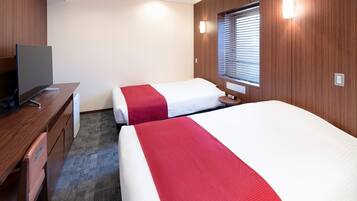 Quarto de hotel com duas camas, uma escrivaninha, televisão e janela com persianas.