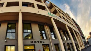 Um hotel com fachada curva, vários andares e um letreiro chamativo com a palavra 'HOTEL'.