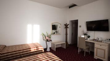Quarto de hotel com duas camas, uma escrivaninha, uma cadeira, uma televisão e um espelho.