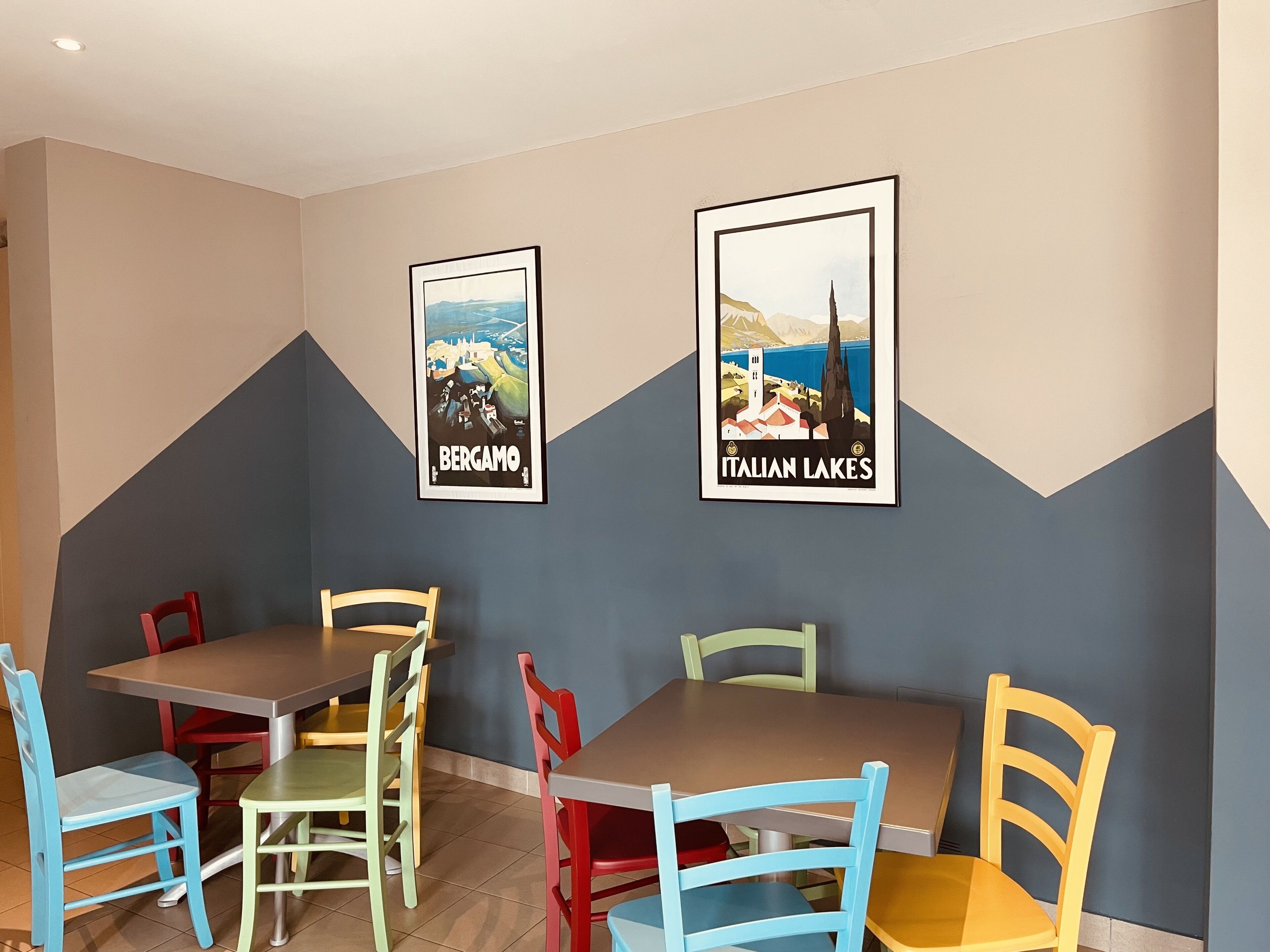 Uma sala de jantar com uma mesa e cadeiras, duas molduras com quadros na parede e um piso de azulejos.
