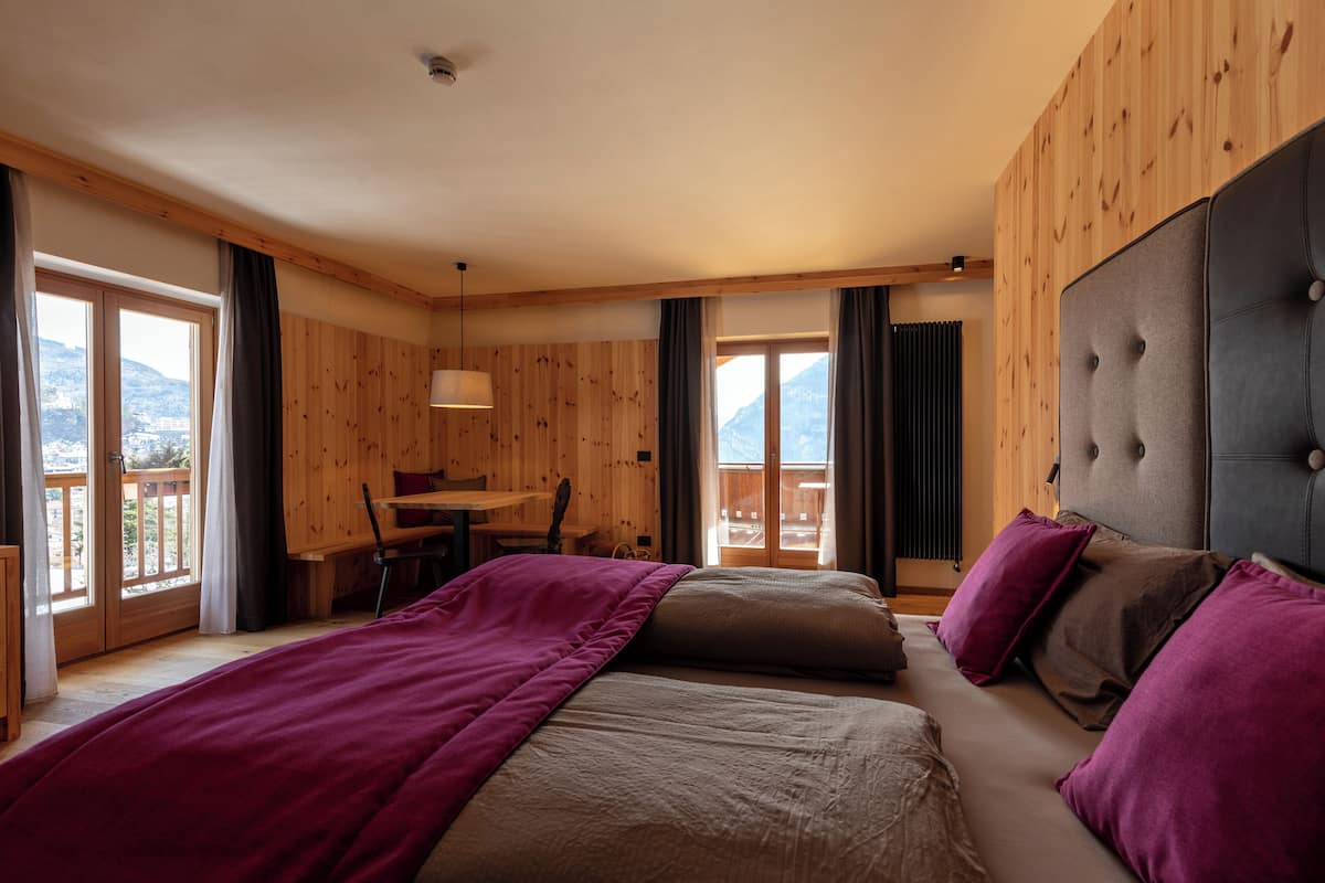 Quarto com uma cama grande, uma escrivaninha e vista para uma montanha.
