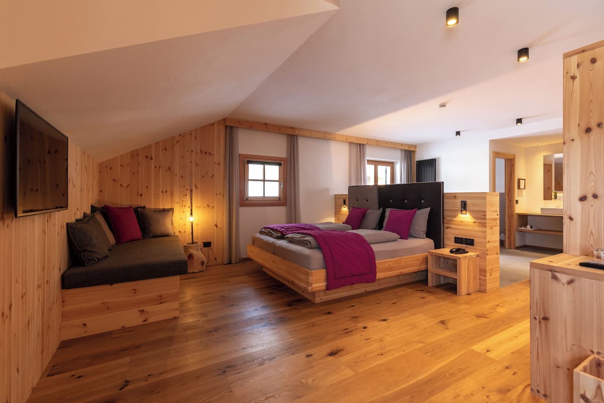 Um quarto moderno com design de estilo loft, apresentando piso de madeira, cama com encosto, uma mesinha de cabeceira e TV integrada.