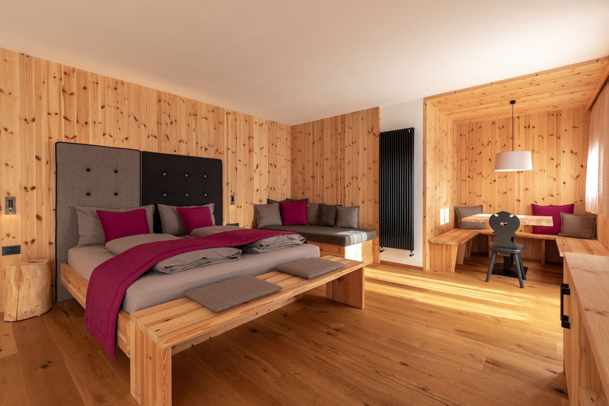Quarto com painéis de madeira, cama, área de estar e escrivaninha.