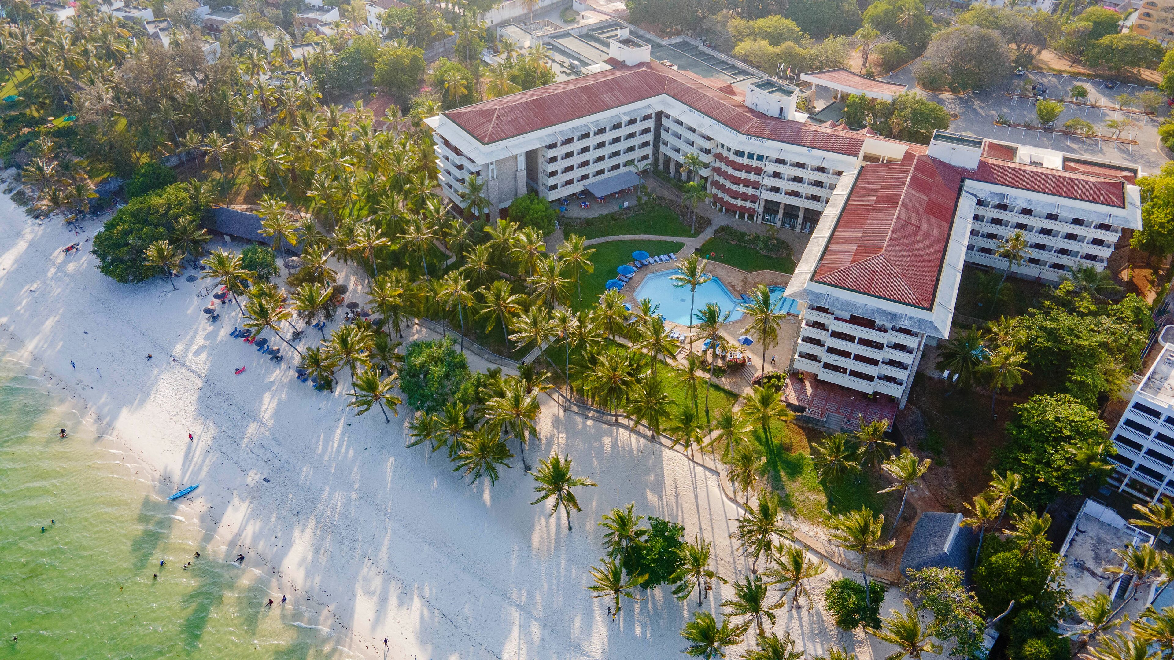 Vista aérea de um resort com um edifício grande, piscina e praia.