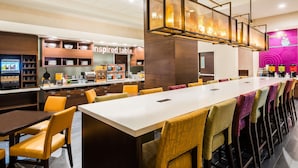 Um restaurante moderno com uma mesa comunitária grande, assentos individuais e uma área de cozinha.