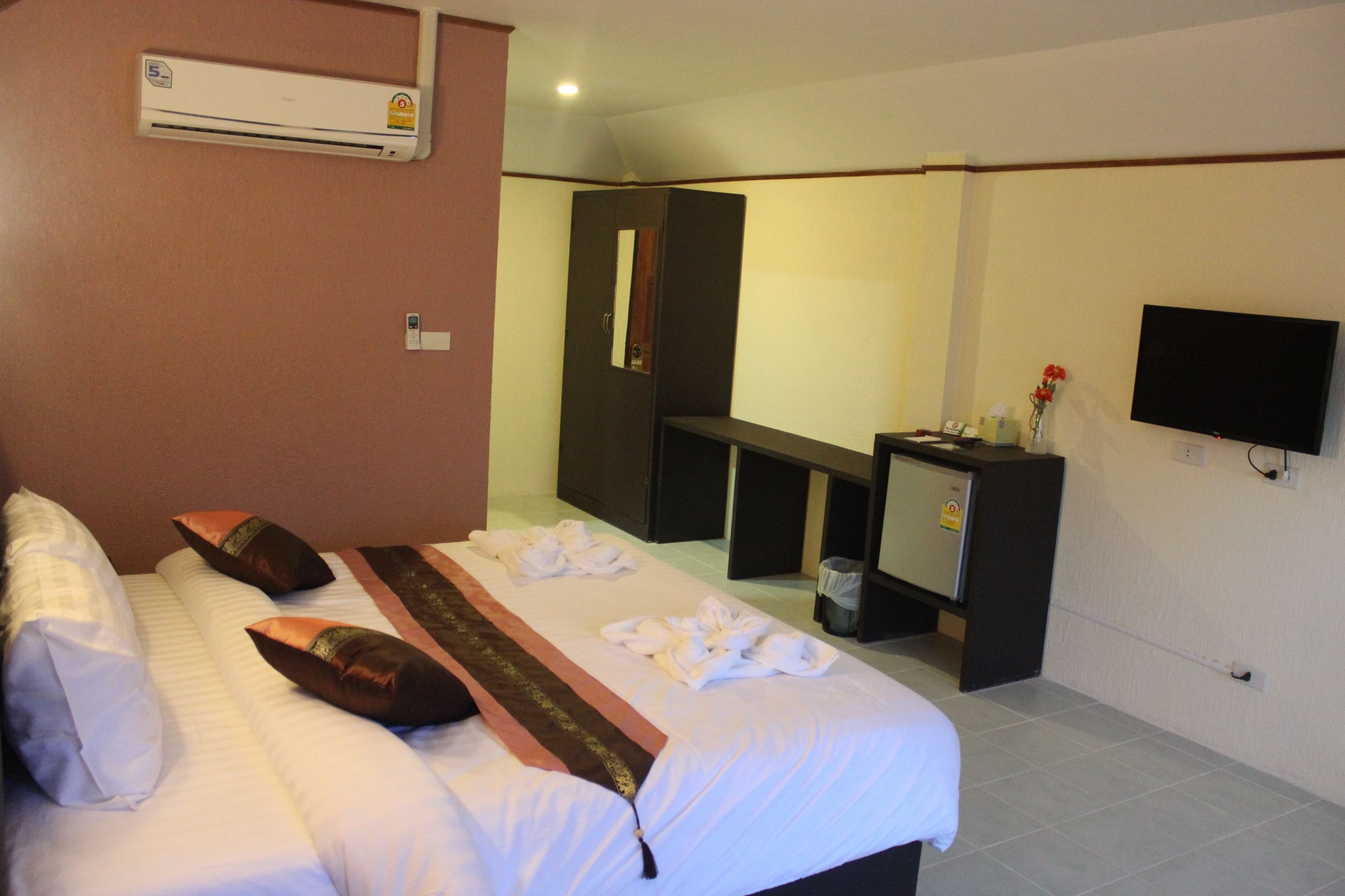 Quarto de hotel com cama, escrivaninha, televisão e ar condicionado.