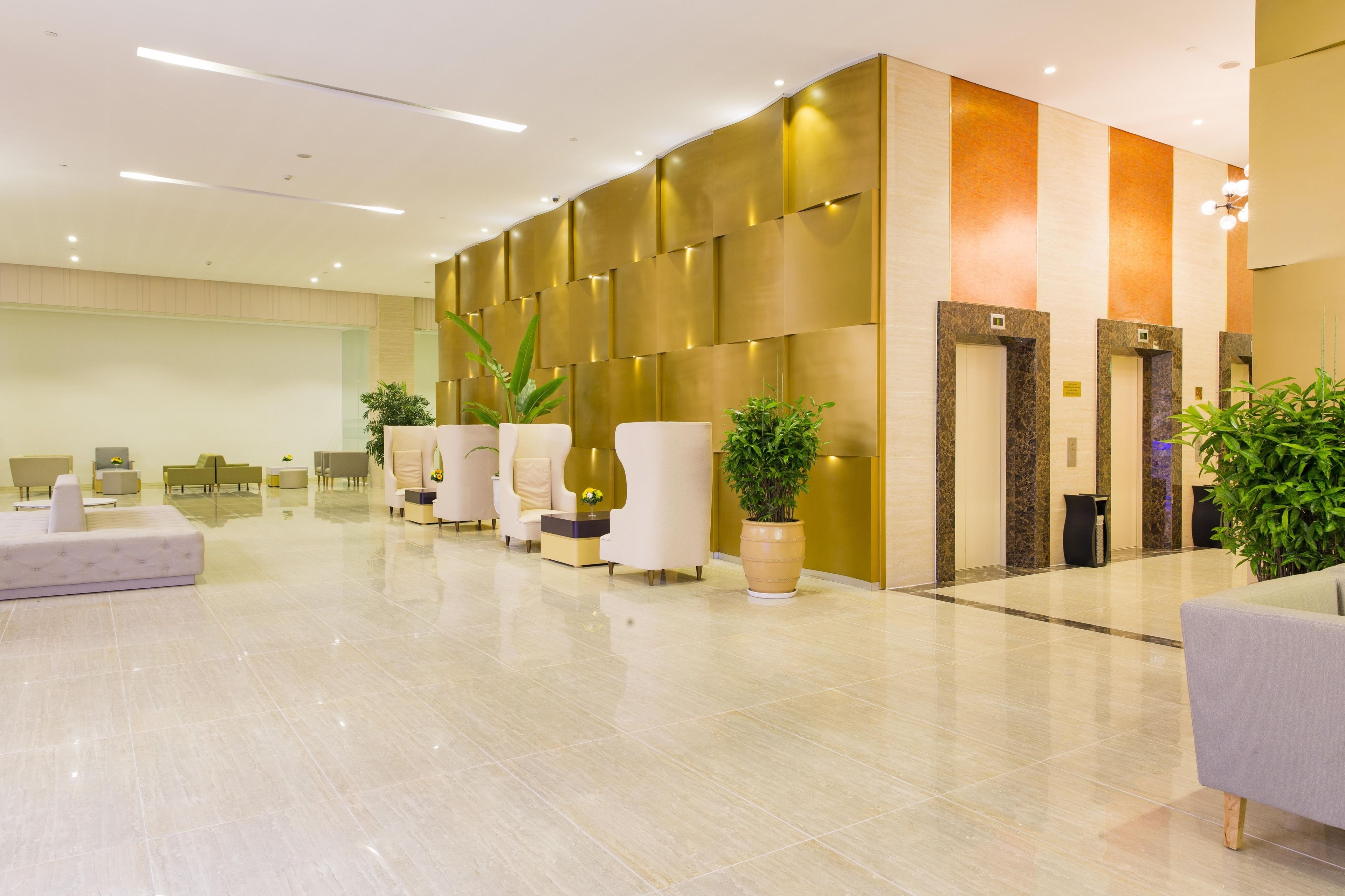Um hall moderno de hotel com balcão de recepção, área de estar e elevadores.