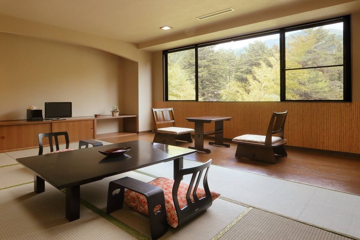 Um quarto em estilo japonês tradicional, com tatames, uma mesa baixa e cadeiras.