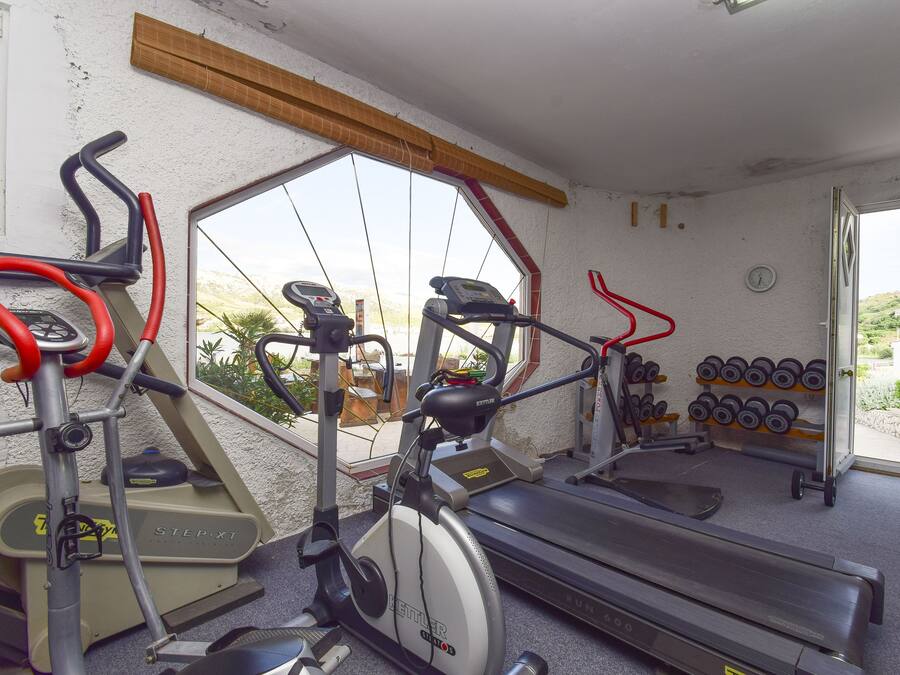 Uma academia com esteiras, bicicletas ergométricas e um suporte de halteres.