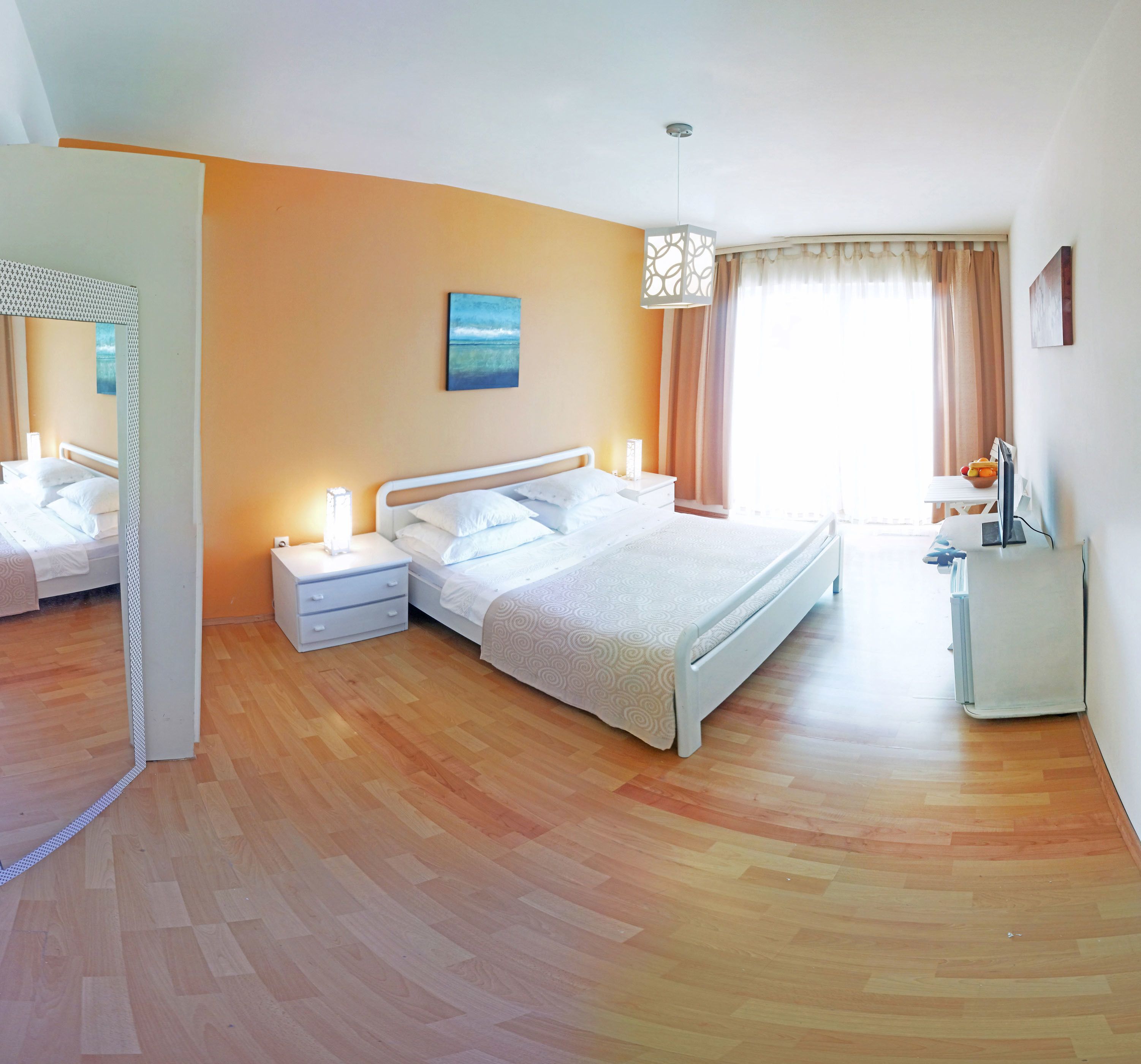 Quarto moderno com cama grande, mesas de cabeceira, escrivaninha e uma cadeira.
