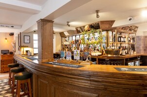 Uma área de bar com banquetas de madeira, diversos tipos de garrafas e um letreiro indicando as cervejas 'Classic' e 'Jazz Club'.
