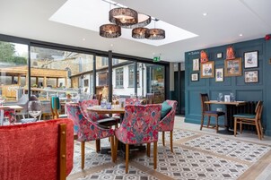 Um restaurante com decoração moderna, com cadeiras estampadas, piso padronizado e parede com quadros.