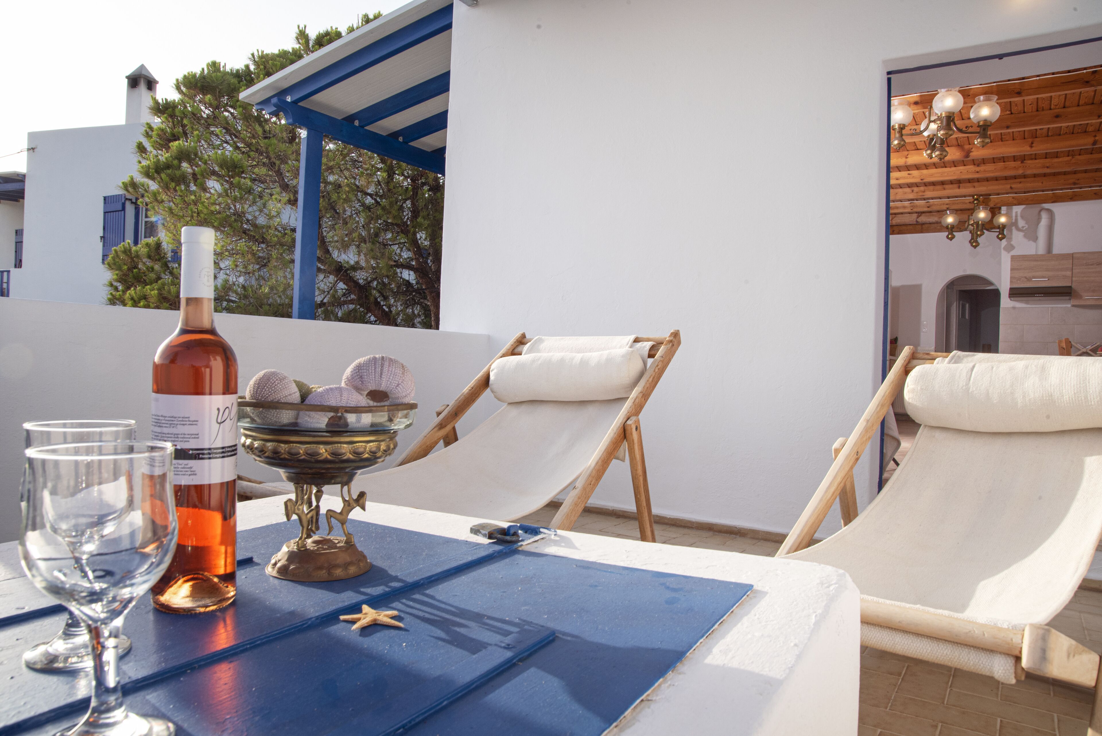 Varanda com mesa posta para dois, uma garrafa de vinho e duas cadeiras de descanso.