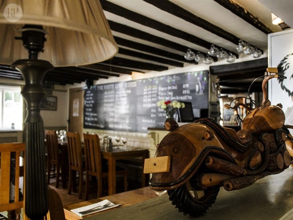 Uma escultura de madeira sobre uma mesa em restaurante, com um quadro de menu ao fundo.