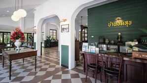 Uma área de recepção com piso xadrez, balcão de recepção e uma parede verde com um aviso.