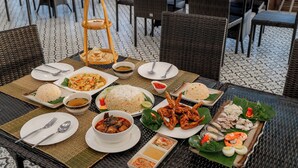 Mesa posta com diversos pratos, incluindo arroz, frutos do mar e uma cesta de frutas.