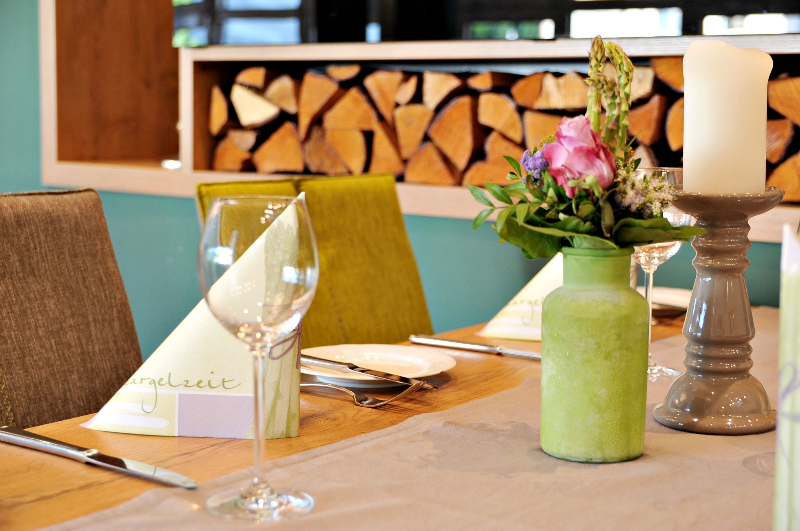 Uma mesa de jantar posta, com um vaso verde, uma vela e um cardápio.