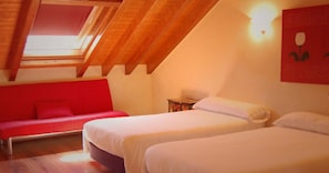 Quarto com duas camas, um sofá vermelho, um claraboia e um aplique na parede.