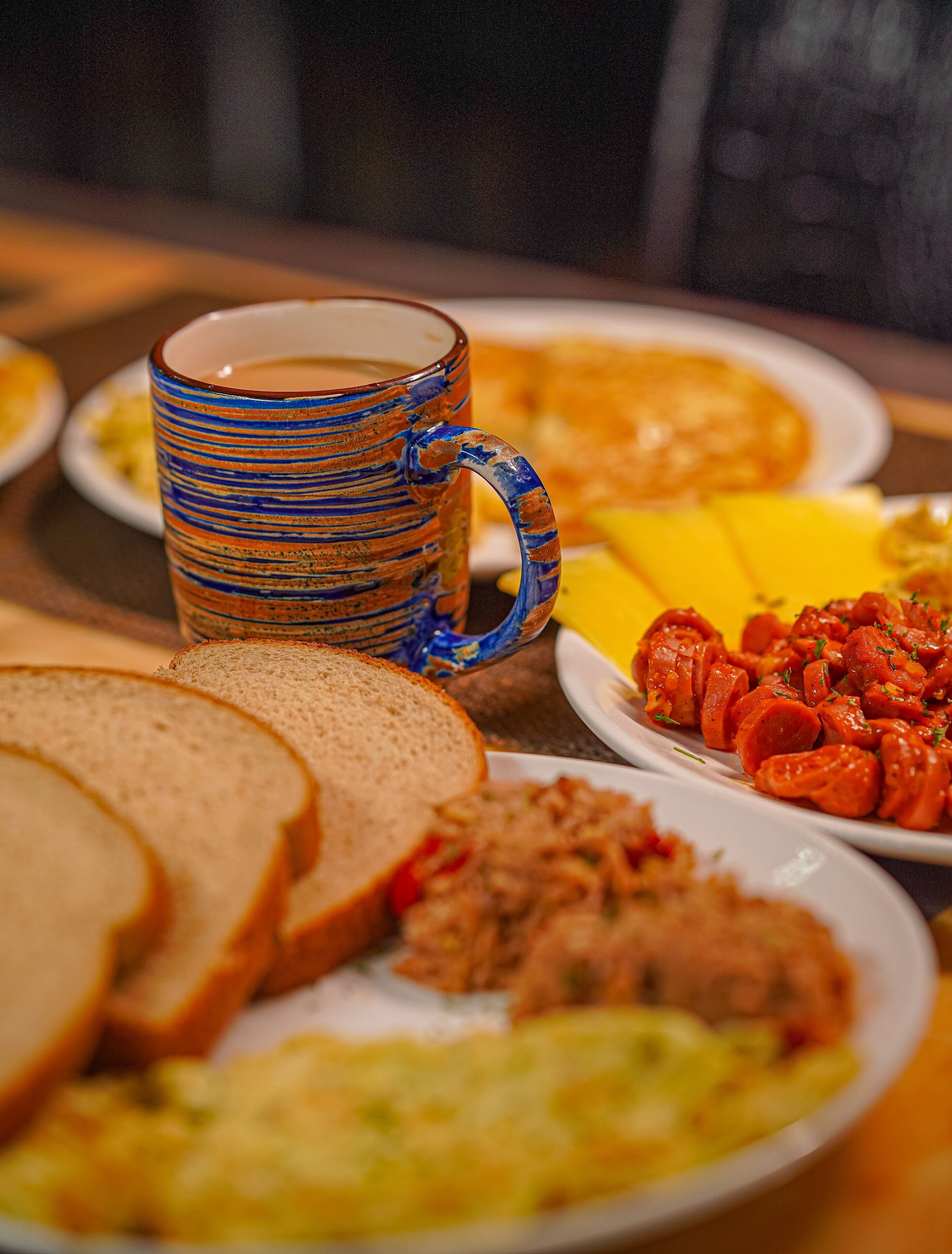 Uma mesa com diversas opções de pequeno-almoço, incluindo pão, ovos e uma chávena.