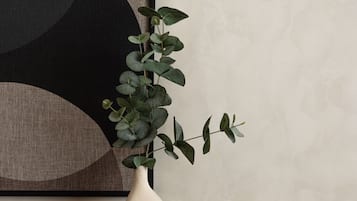 Um vaso com uma planta sobre uma mesa de madeira em frente a uma parede com arte abstrata.
