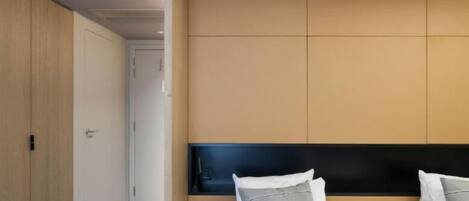 Quarto de hotel com cama, cabeceira, guarda-roupa e uma porta.