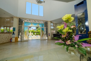 Um saguão de hotel com balcão de recepção, uma janela ampla e uma entrada decorativa.