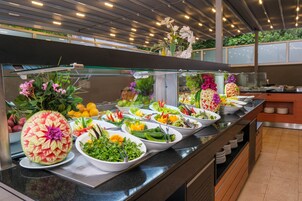 Buffet com diversos alimentos e uma decoração central de abacaxi.