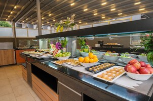 Buffet com diversos alimentos e frutas frescas.