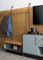 Quarto com parede de madeira, televisão montada, um banco com espaço de armazenamento embaixo e um sapateiro.