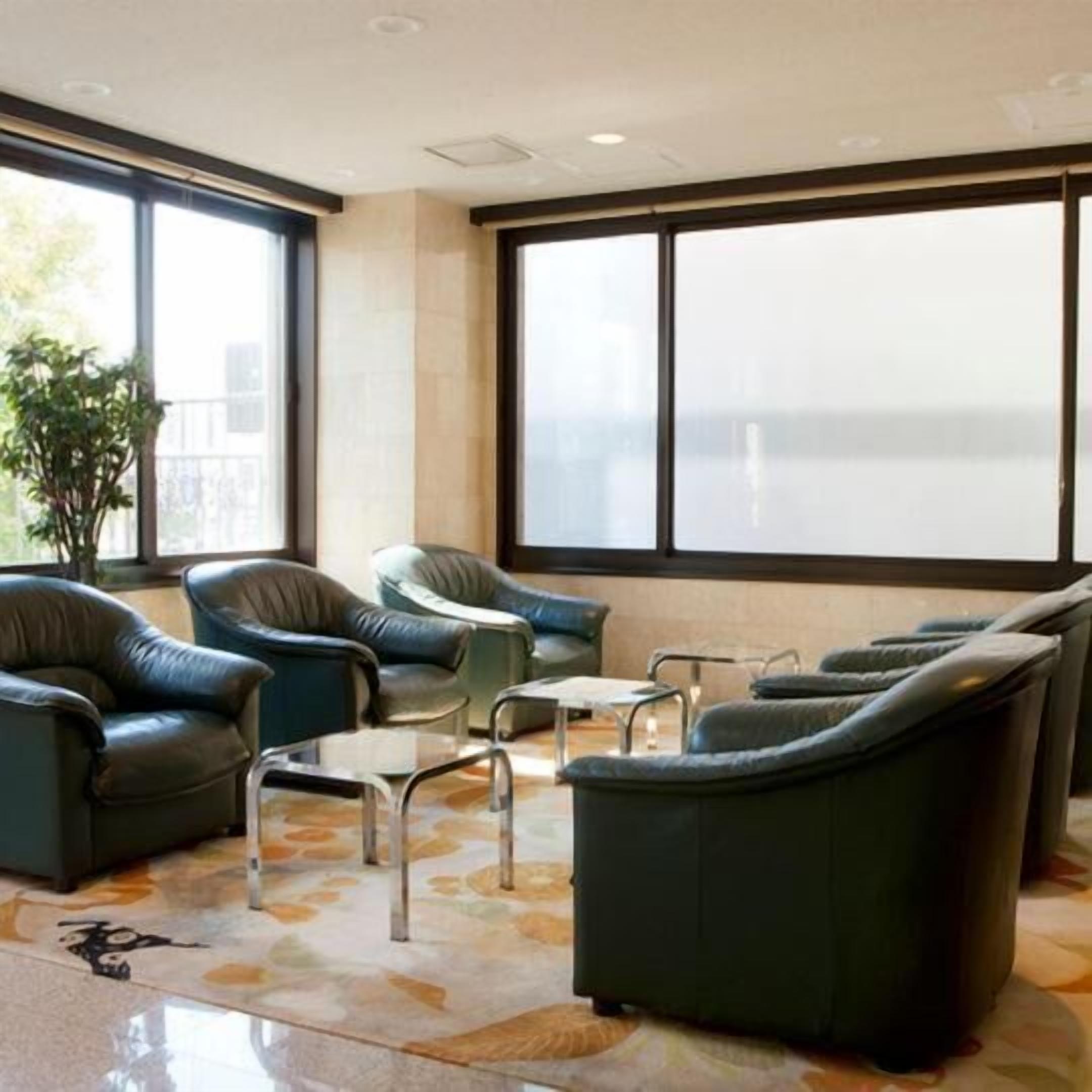 Uma área de estar moderna com sofás de couro, uma mesa de centro e grandes janelas com vista.