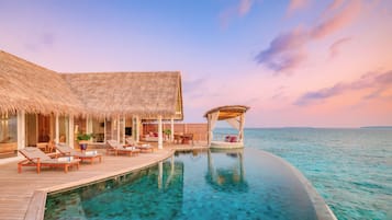 Uma piscina infinita luxuosa, com água cristalina, deck de madeira e espreguiçadeiras.