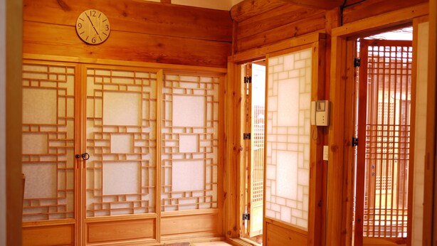 Quarto japonês tradicional com tatames, portas corrediças e uma mesa de madeira com um laptop.