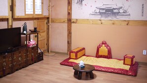 Quarto em estilo tradicional com um armário de madeira, uma televisão, uma parede decorativa com uma pintura e uma mesinha de madeira com um bule.