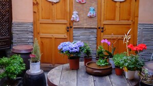 Uma porta de madeira com uma placa, uma mesa de madeira com plantas em vasos e uma parede de pedra.
