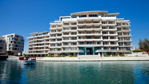 Um hotel com vários andares e varandas, situado perto de um corpo de água.