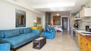 Uma sala de estar moderna com um sofá azul, uma mesa de centro e uma área de jantar com uma mesa e cadeiras.