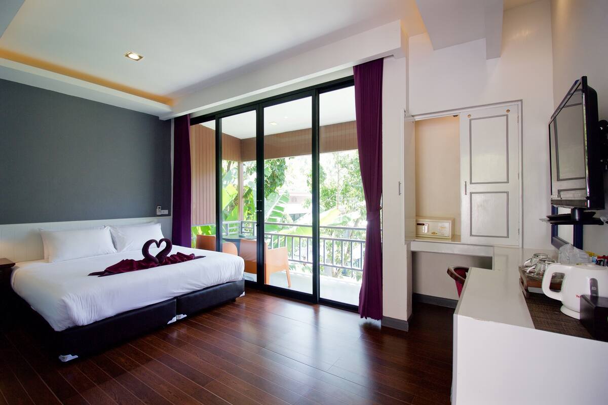 Quarto de hotel com uma cama grande, varanda com vista, televisão e cozinha compacta.