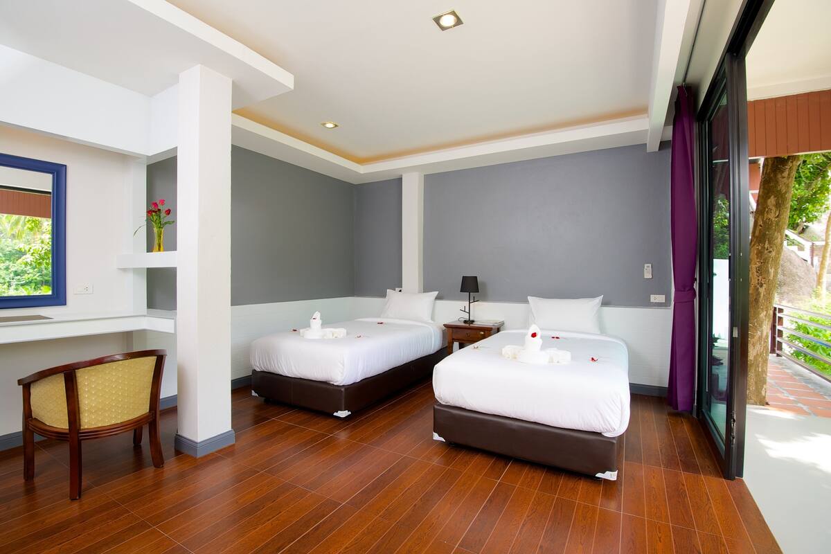 Quarto de hotel com duas camas, uma escrivaninha e uma cadeira.