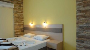 Quarto de hotel moderno com cama, mesa de cabeceira e luminárias fixadas na parede.